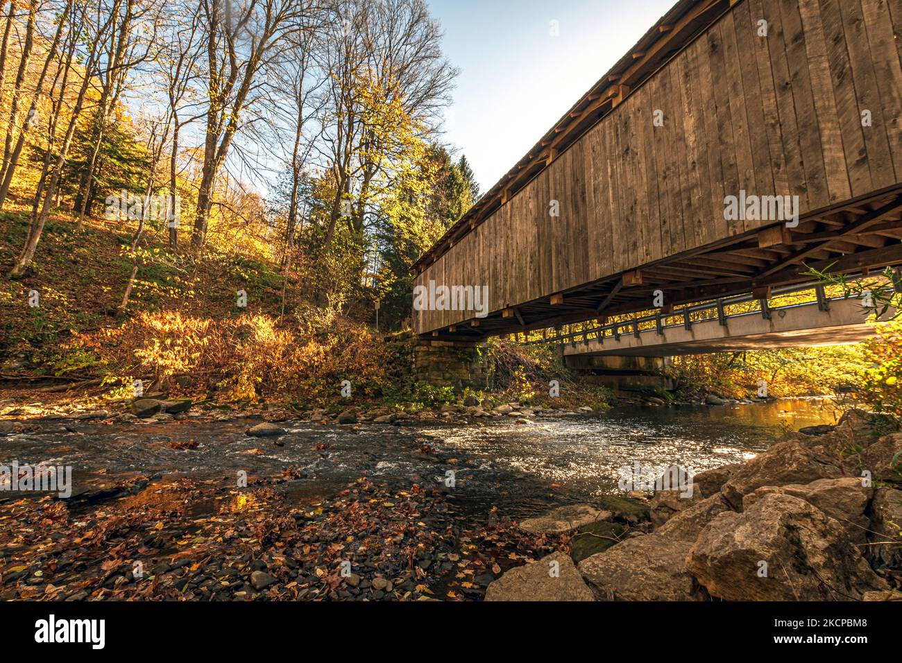 Rural autumn landscape of a wooden covered bridge over a creek during ...