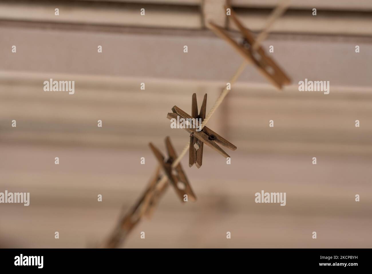 A line of old wooden clothes pegs on a nylon washing line with rusty ...