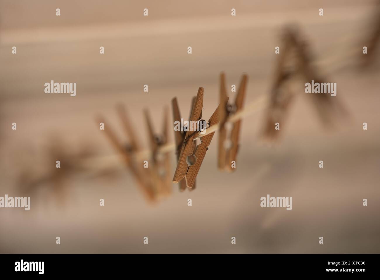 A line of old wooden clothes pegs on a nylon washing line with rusty ...