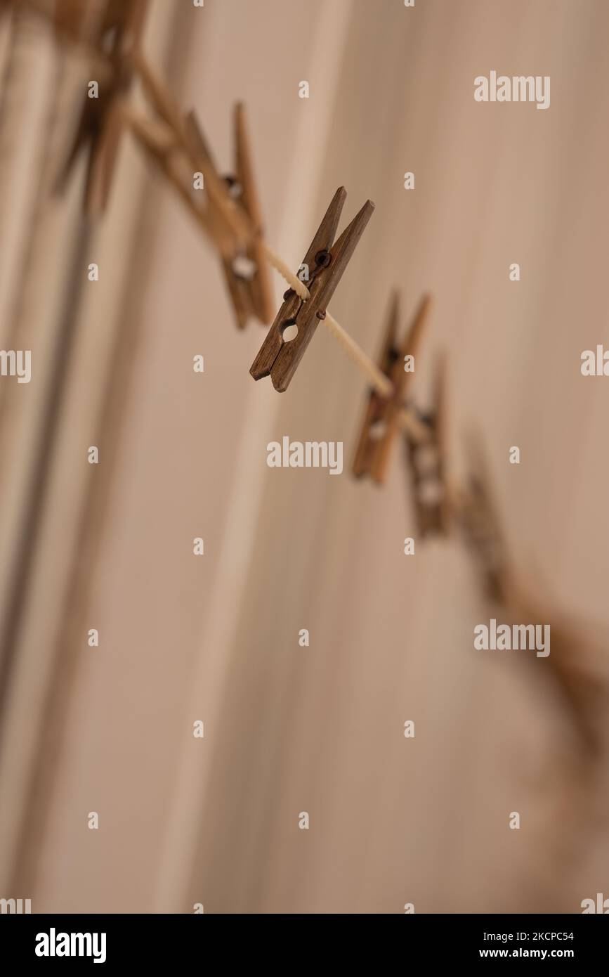 A line of old wooden clothes pegs on a nylon washing line with rusty ...