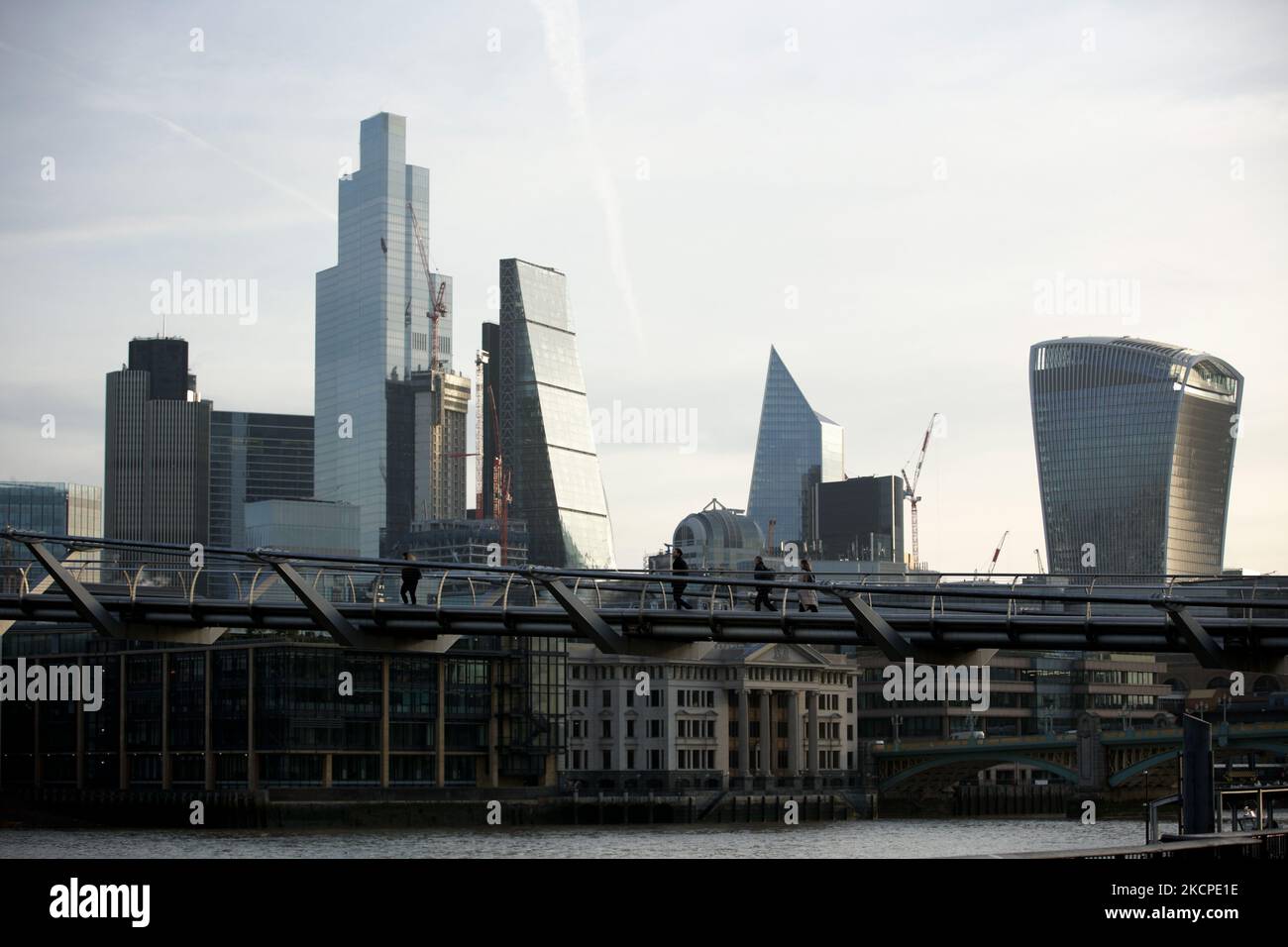 People walk across the Millennium Bridge across the River Thames as ...