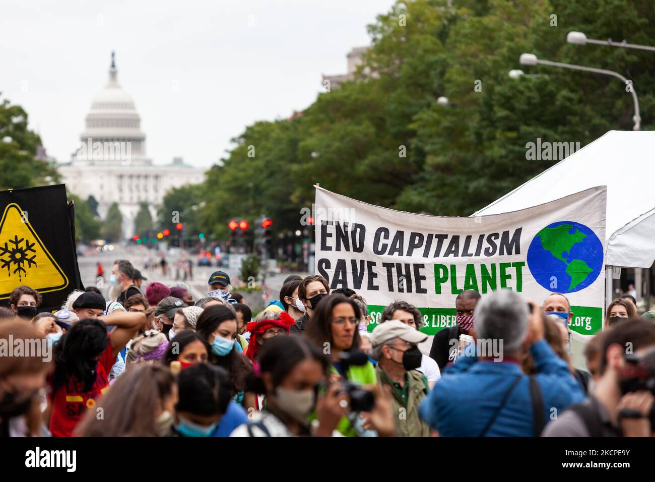 Protesters carry a sign linking capitalism to the climate crisis as ...