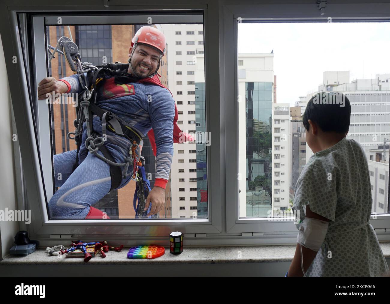Window cleaners wearing superhero costumes greet a patient at a ...