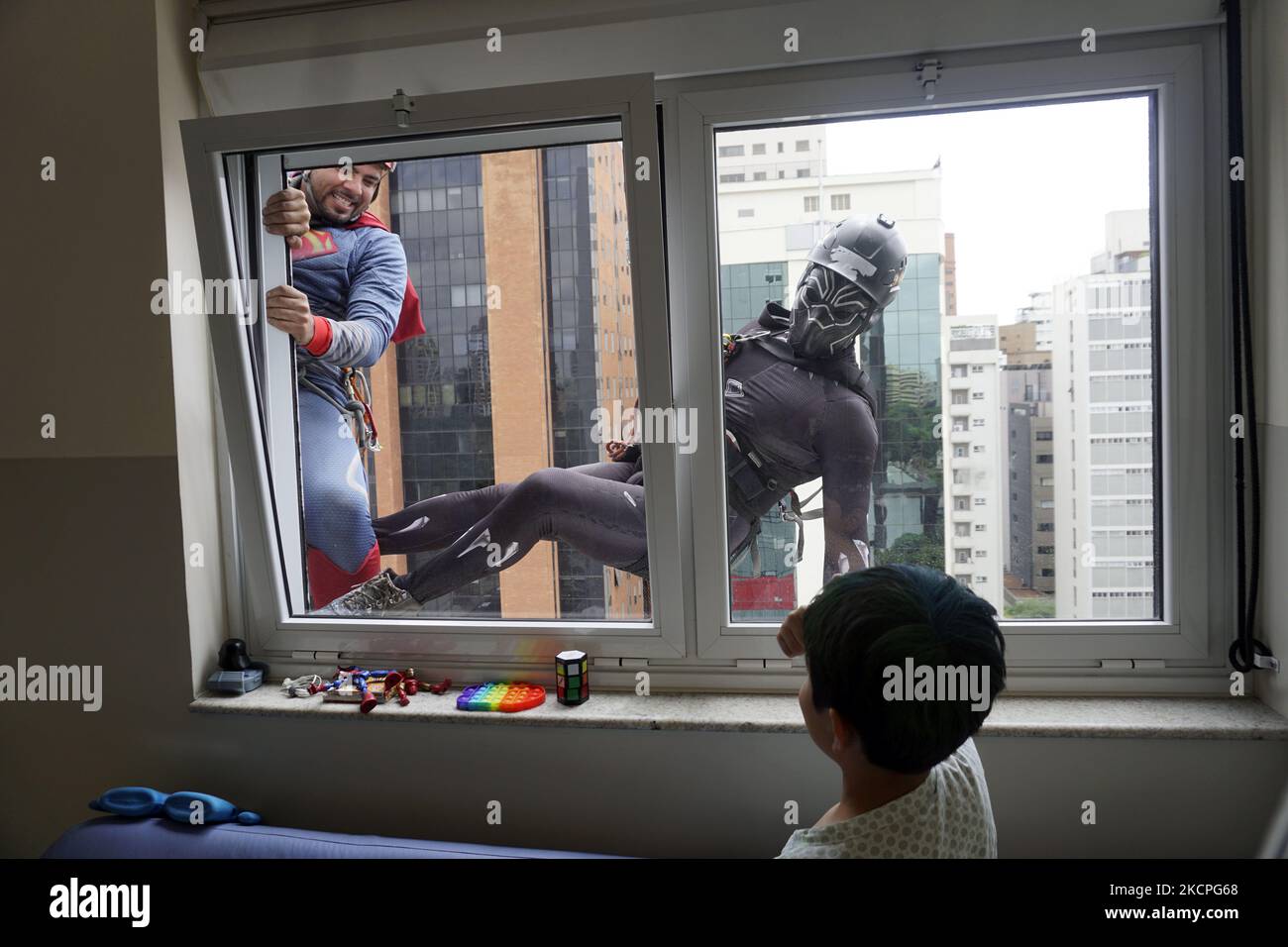 Window cleaners wearing superhero costumes greet a patient at a ...