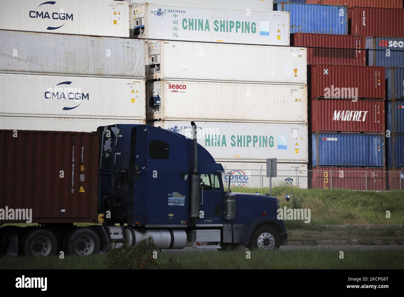 An eighteen-wheeler passes a row of stacked shipping containers at The ...
