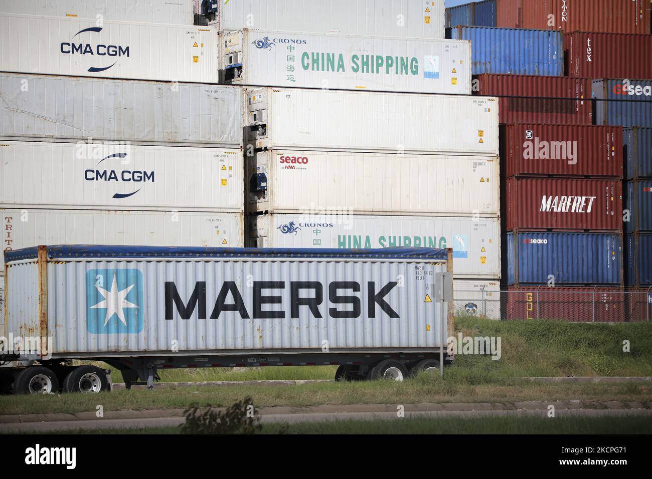 An eighteen-wheeler passes a row of stacked shipping containers at The ...