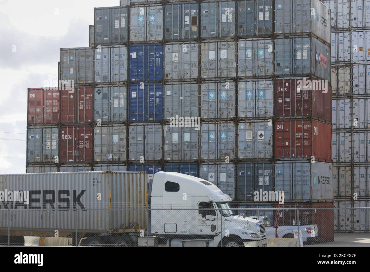 An eighteen-wheeler passes a row of stacked shipping containers at The ...