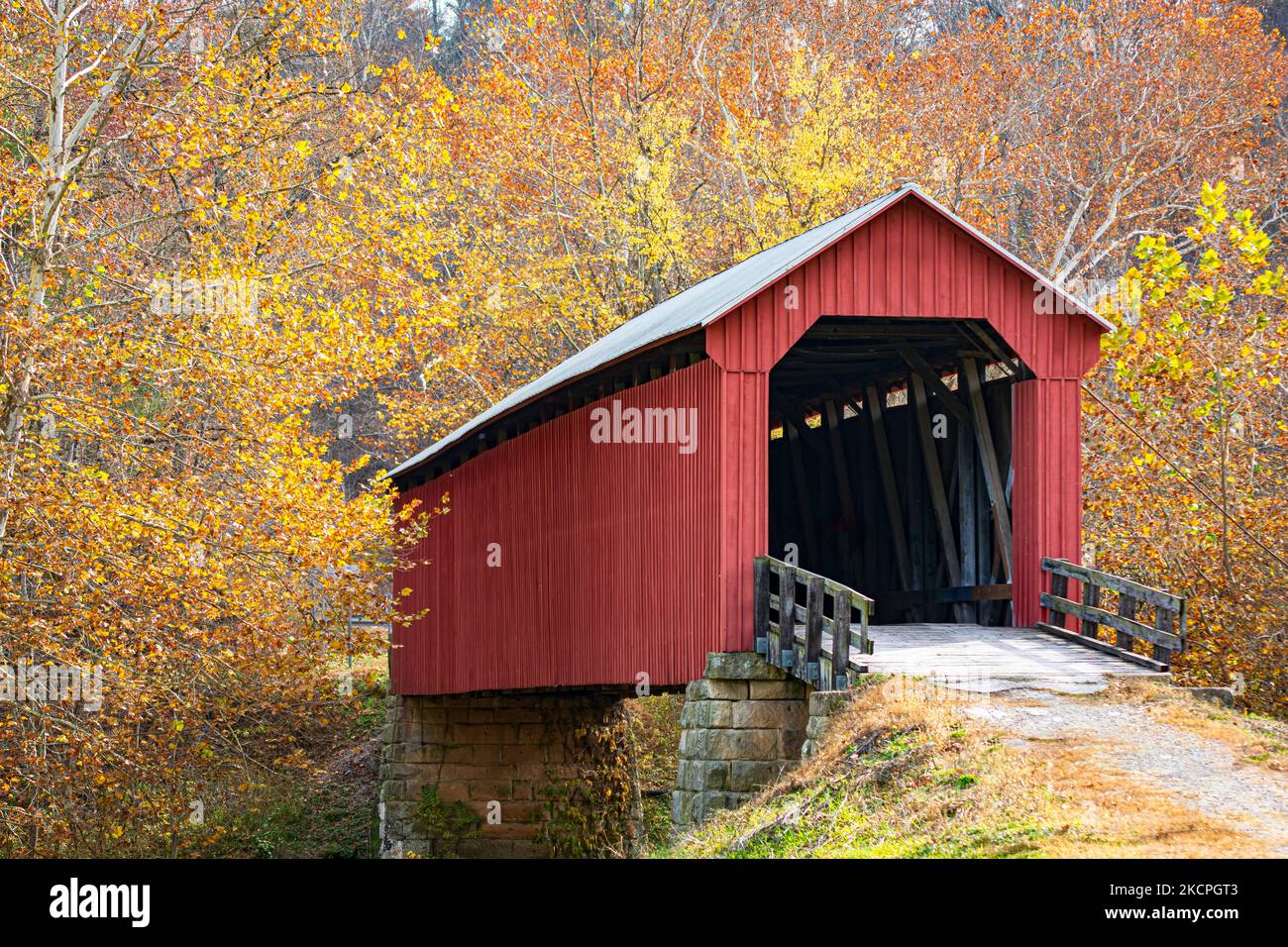 Red traditional covered bridge surrounded by bright autumn foliage in ...