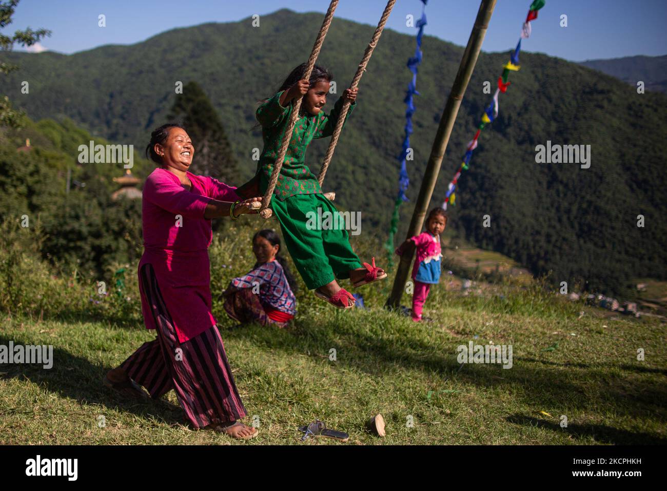A woman helps a kid to ride a traditional swing set up as part Dashain ...