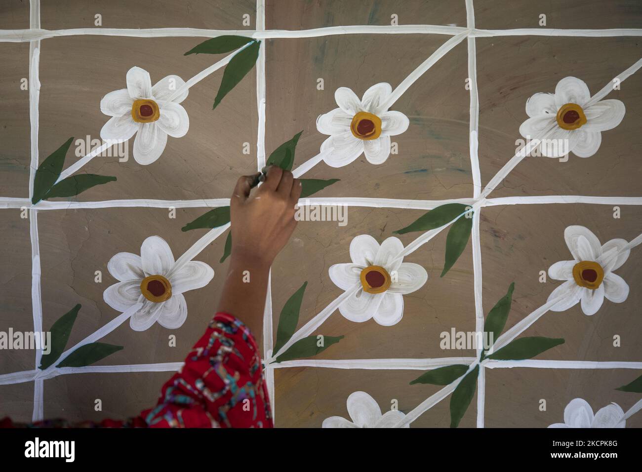 A resident paints alpine on a wall at Alpona village in chapainawabganj ...