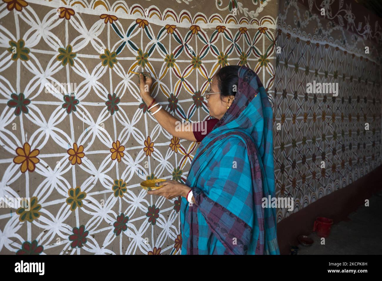 A resident paints alpine on a wall at Alpona village in chapainawabganj ...