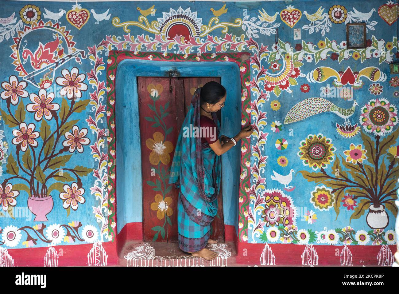 A resident paints alpine on a wall at Alpona village in chapainawabganj ...
