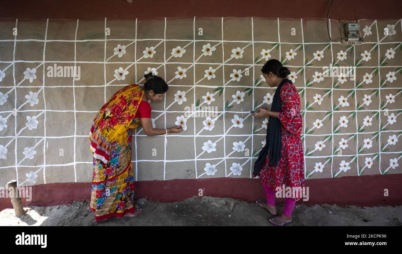 A resident paints alpine on a wall at Alpona village in chapainawabganj ...