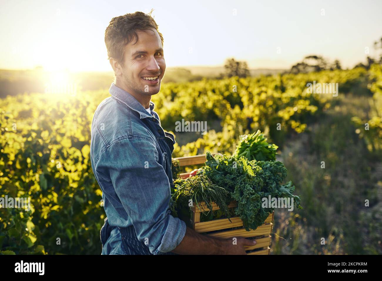 I do it for the love of farming. a young man holding a crate full of ...