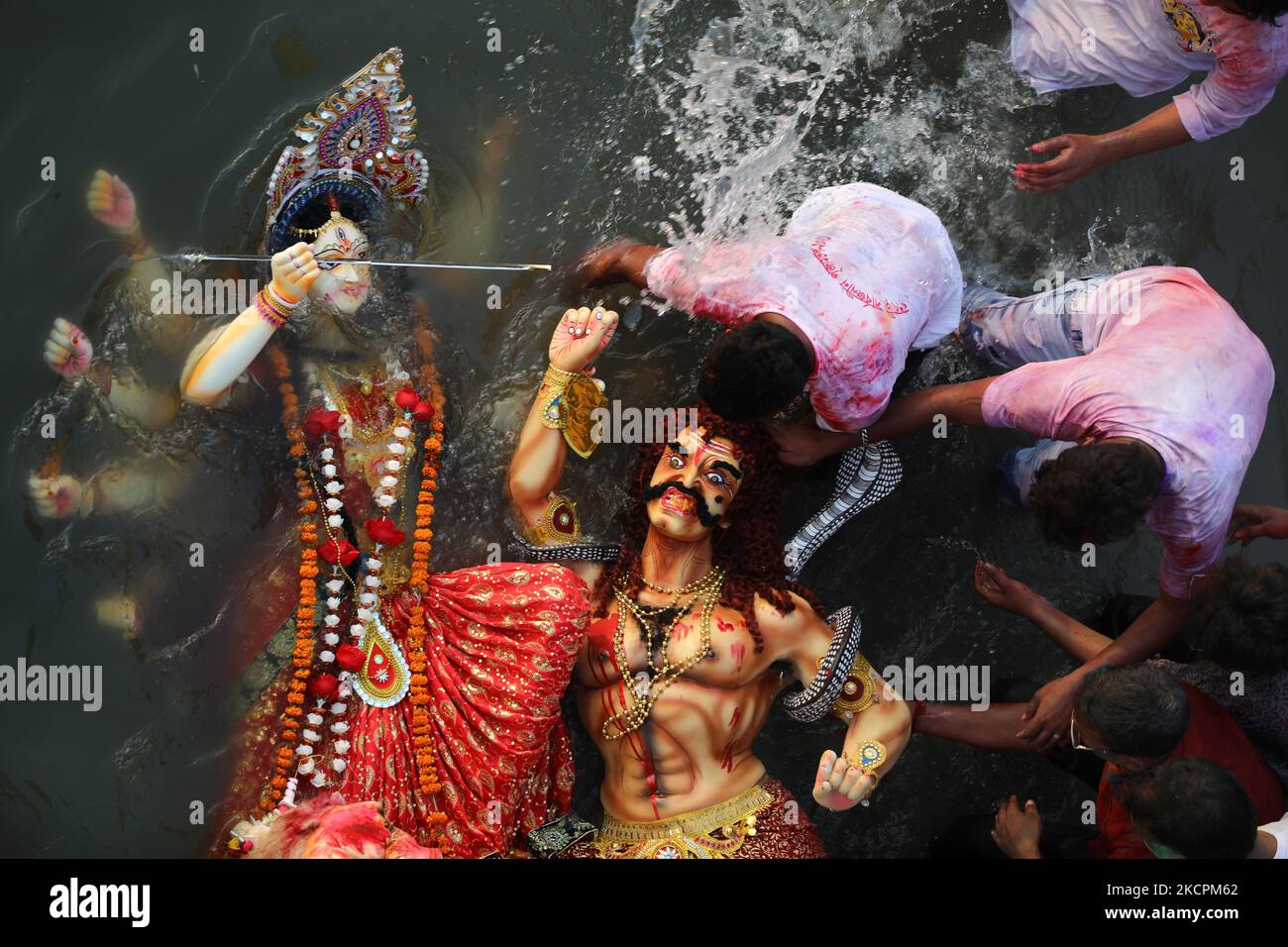 Hindu devotees immerse a clay idol of the Hindu Goddess Durga in the ...