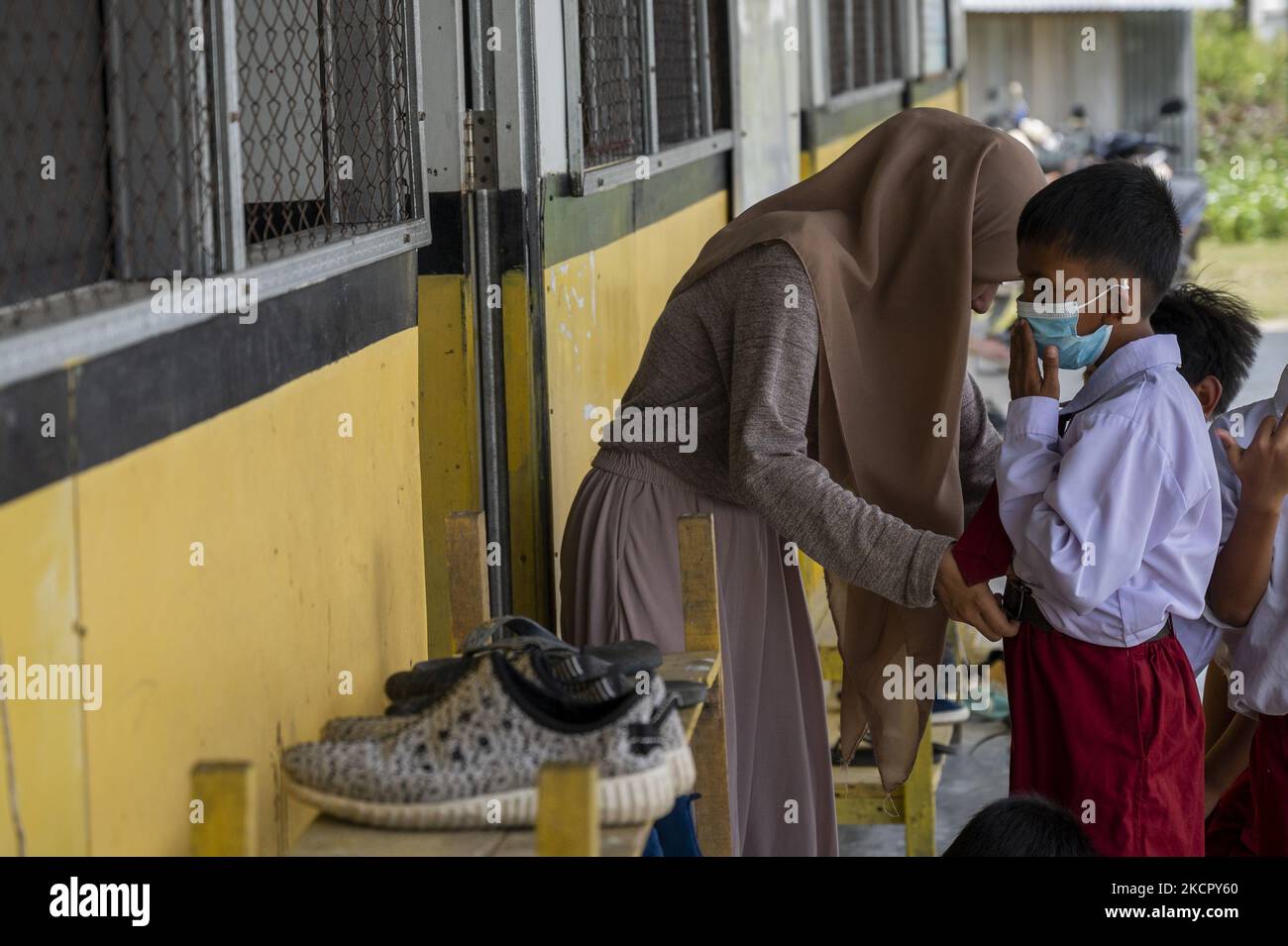 A teacher fixes a student's clothes during the first Face-to-face ...