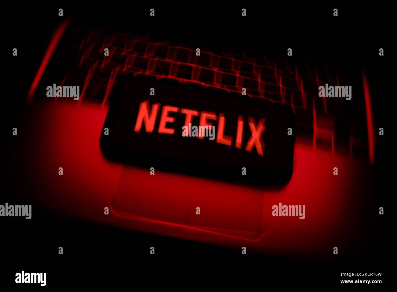 Netflix logo displayed on a phone screen and a laptop keyboard are seen ...