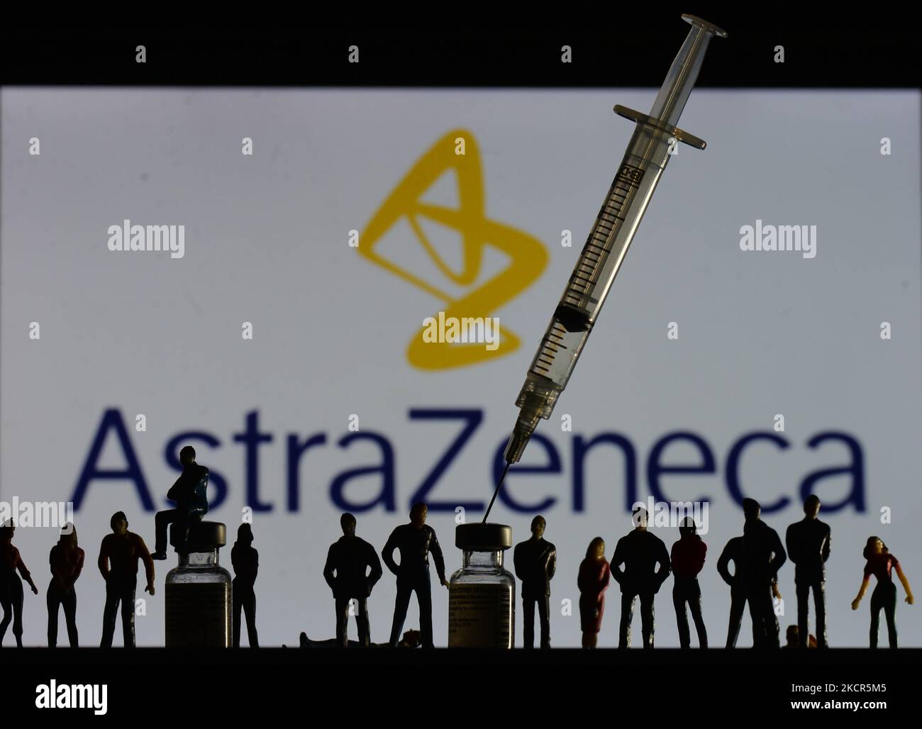 Medical syringe, vaccine vials and small figurines of people are seen ...