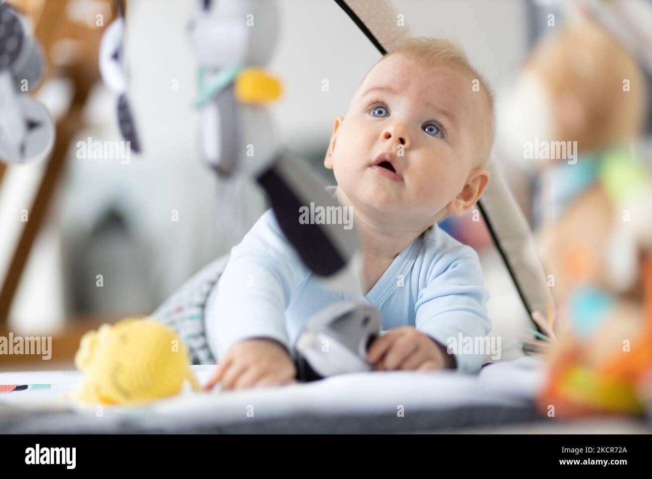 Cute baby boy playing with hanging toys arch on mat at home Baby ...