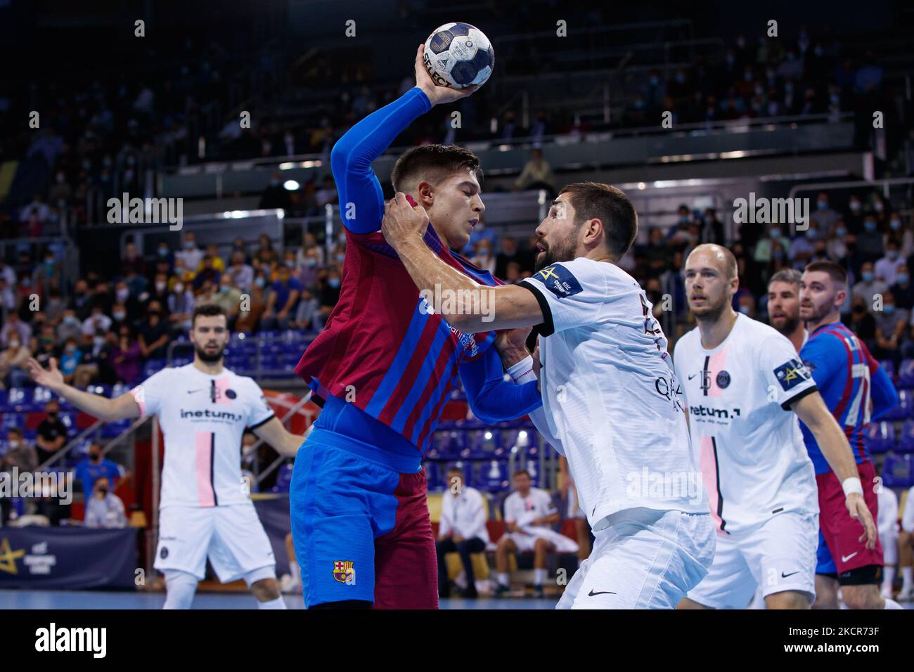 Domen Makuc of FC Barcelona in action with Nikola Karabatic of PSG ...
