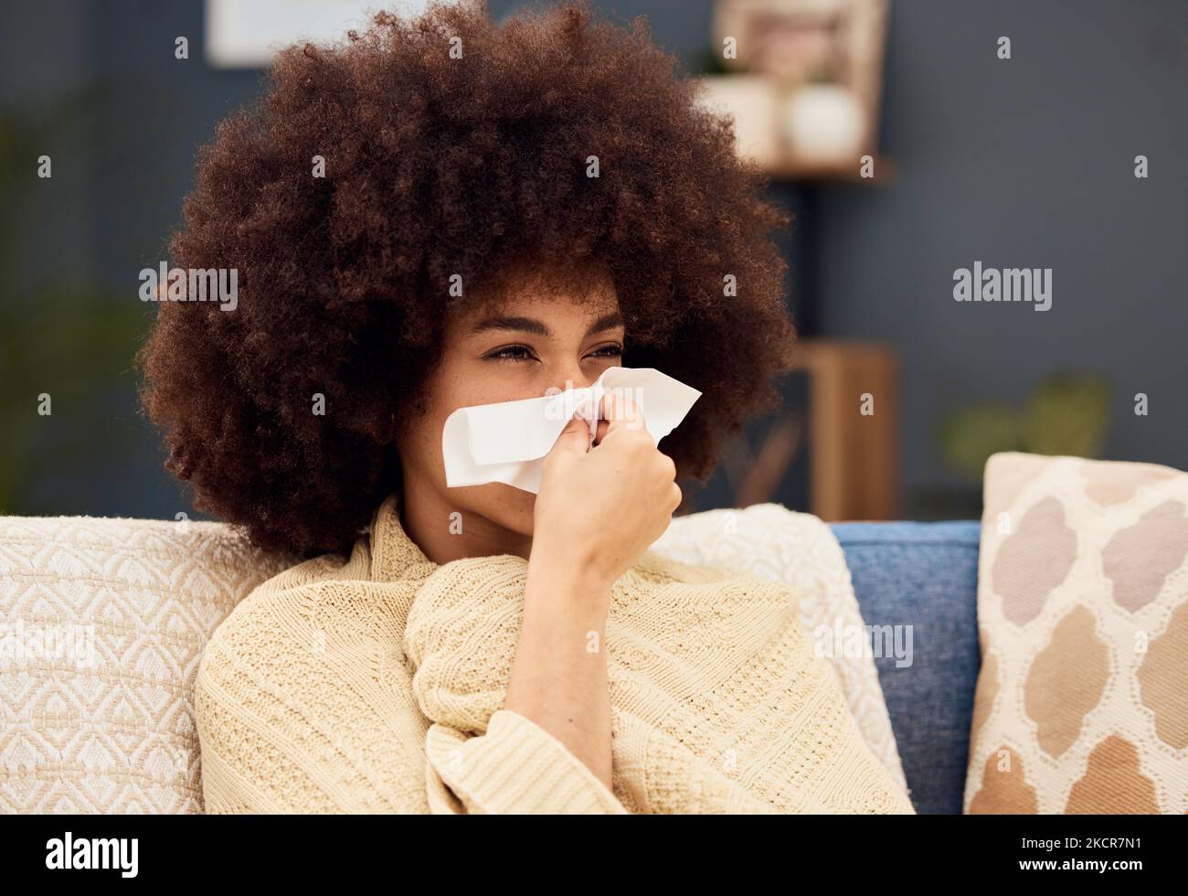 Sick, sad and woman with covid blowing nose on the sofa with a blanket ...
