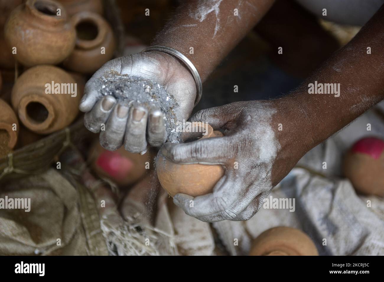 Indian worker puts gun powder inside a clay pot to make a firecracker ...