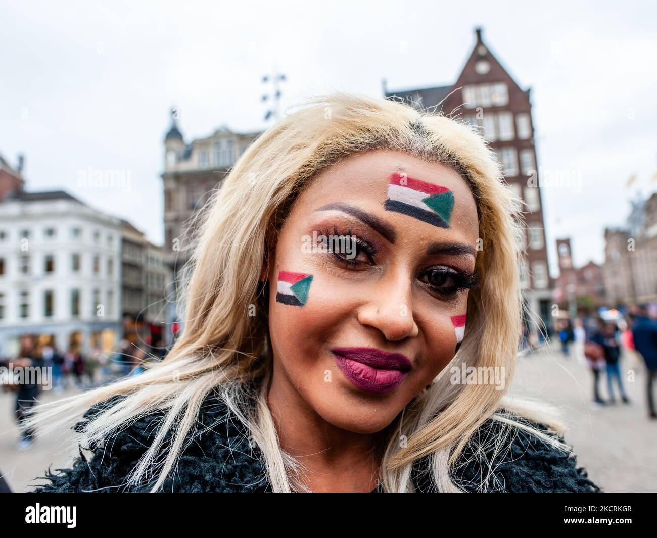 A Sudanese woman has her face painting with Sudanese flags, during a ...