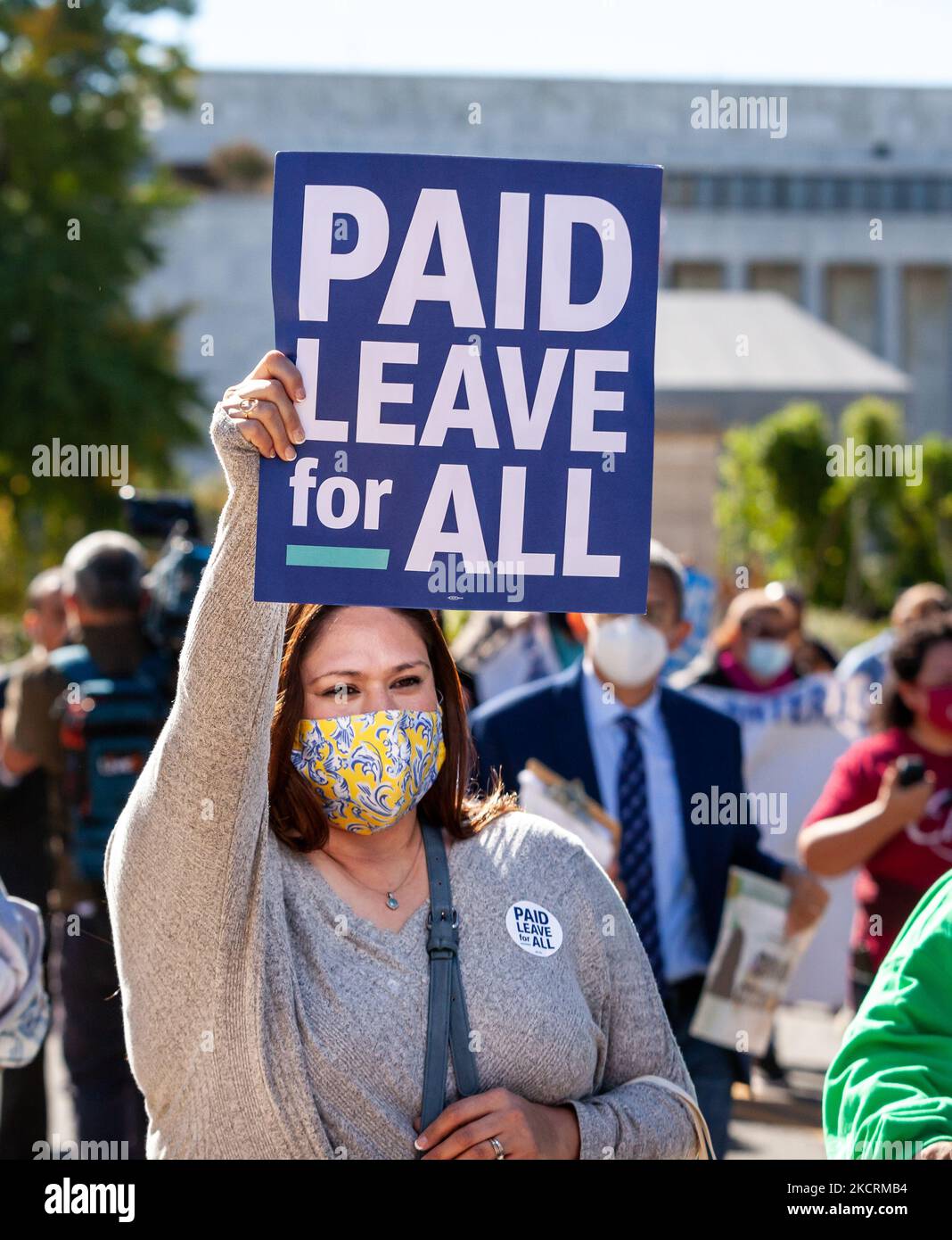 A protester carries a sign demanding "paid leave for all" during a ...