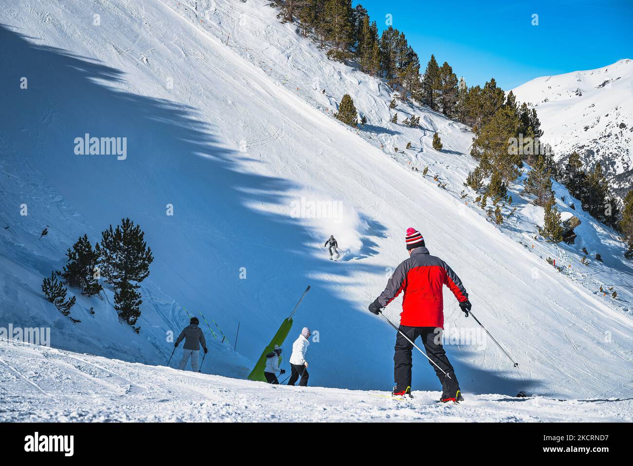 Groups of people on slope junction with focus on fast skier on steep ...