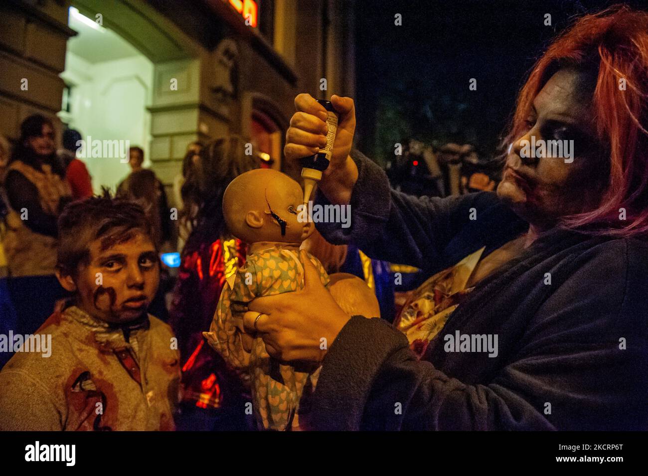 A female zombie is putting fake blood over her fake baby, before the ...