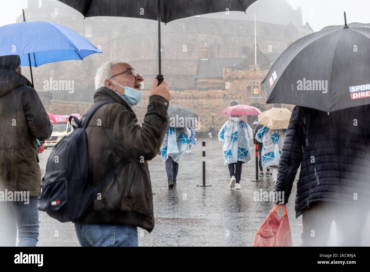 Tourists walk on Royal Mile as autumn weather with rain and wind struck ...