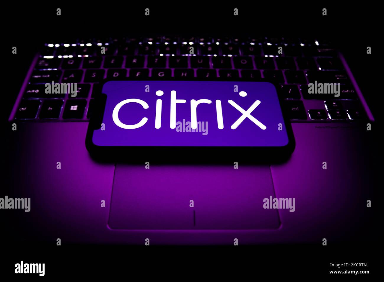 Citrix logo displayed on a phone screen and a laptop keyboard are seen ...