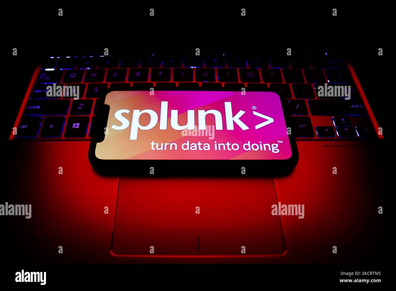 Splunk logo displayed on a phone screen and a laptop keyboard are seen ...