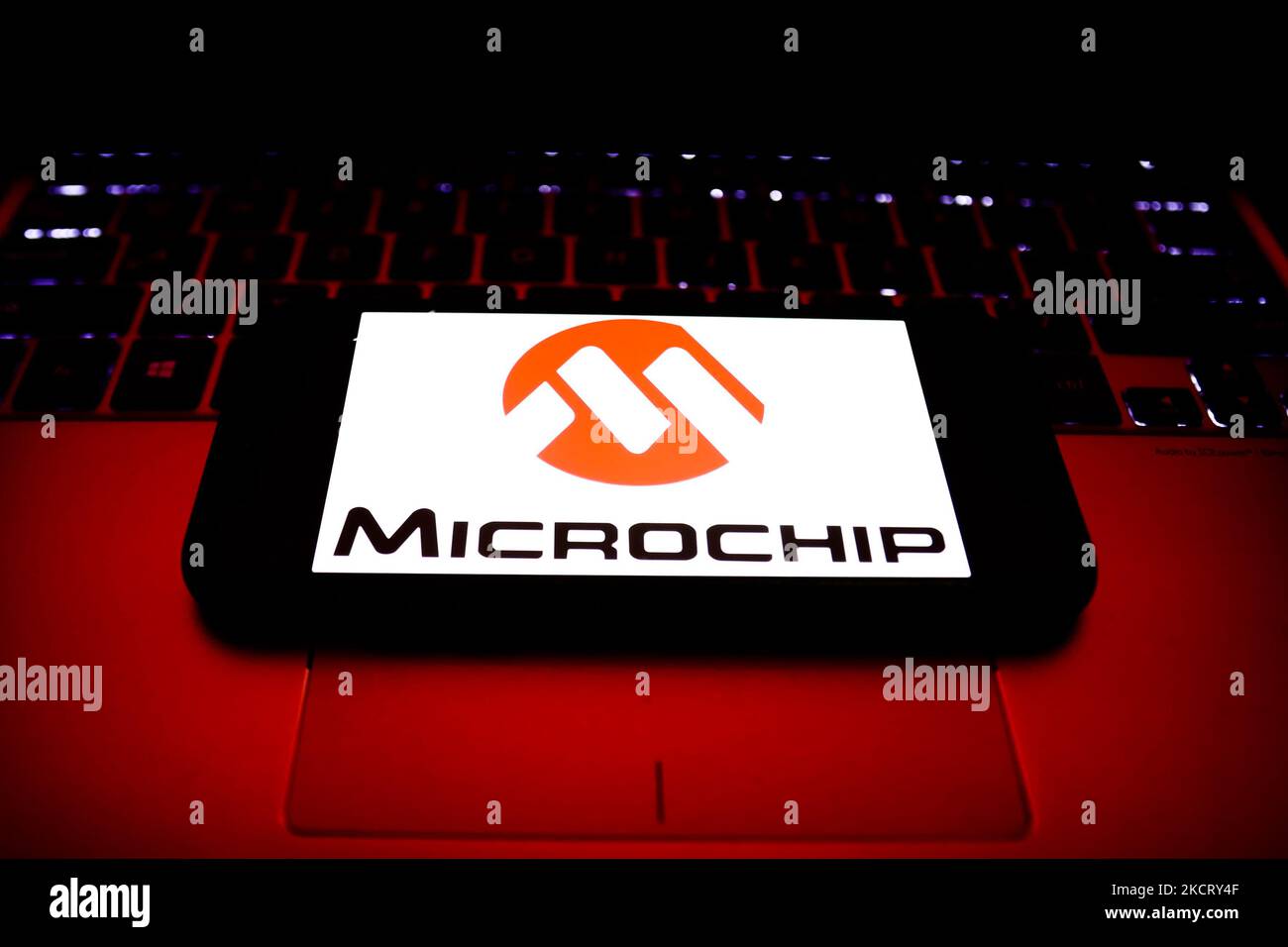 Microchip logo displayed on a phone screen and a laptop keyboard are ...