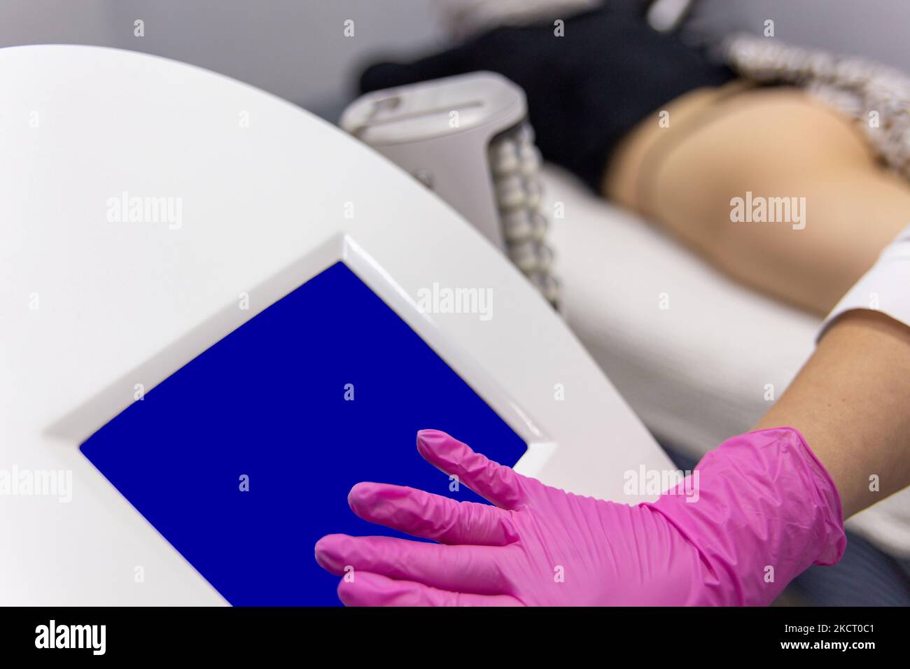 A medic adjusts the operating mode of the anti-cellulite massage ...