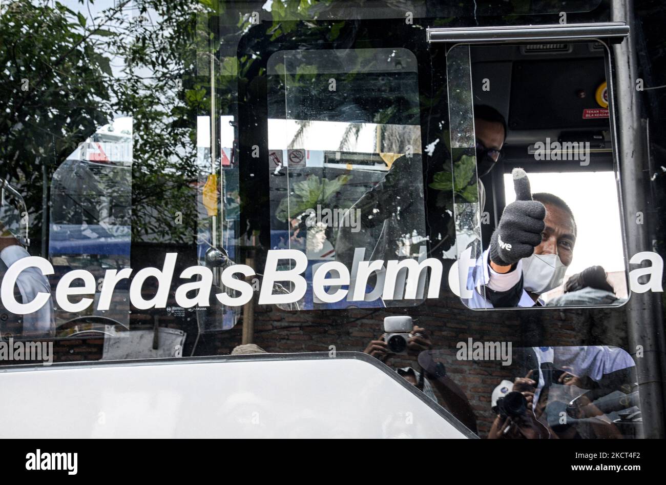 A bus driver gesture his hand as he poses for a photo inside his bus in ...