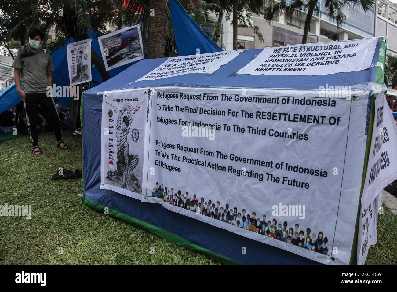 Afghan refugee men living in Indonesia stnd up near in their tent ...