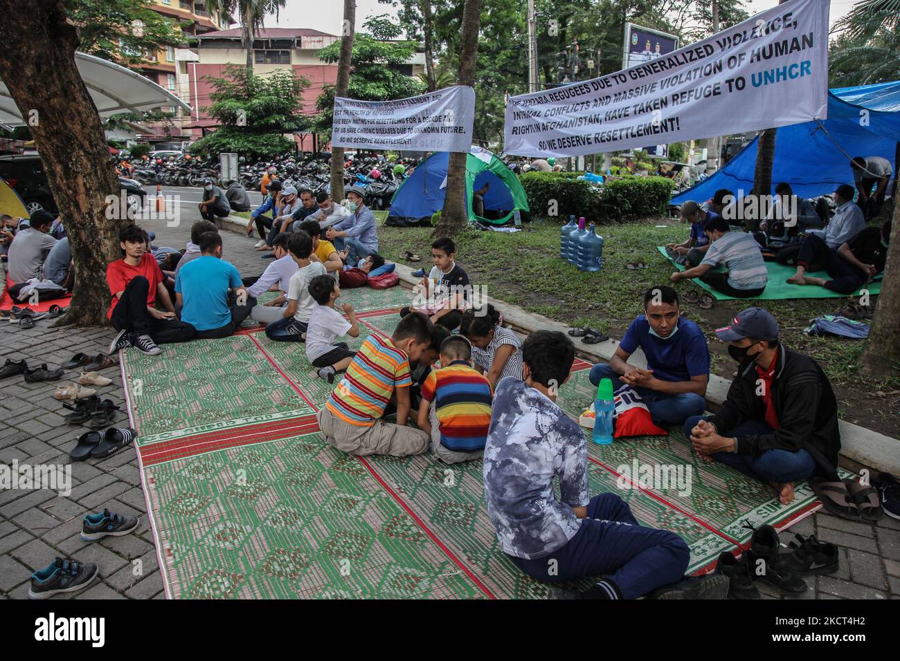 Afghan refugee men living in Indonesia sit in their tent during a ...