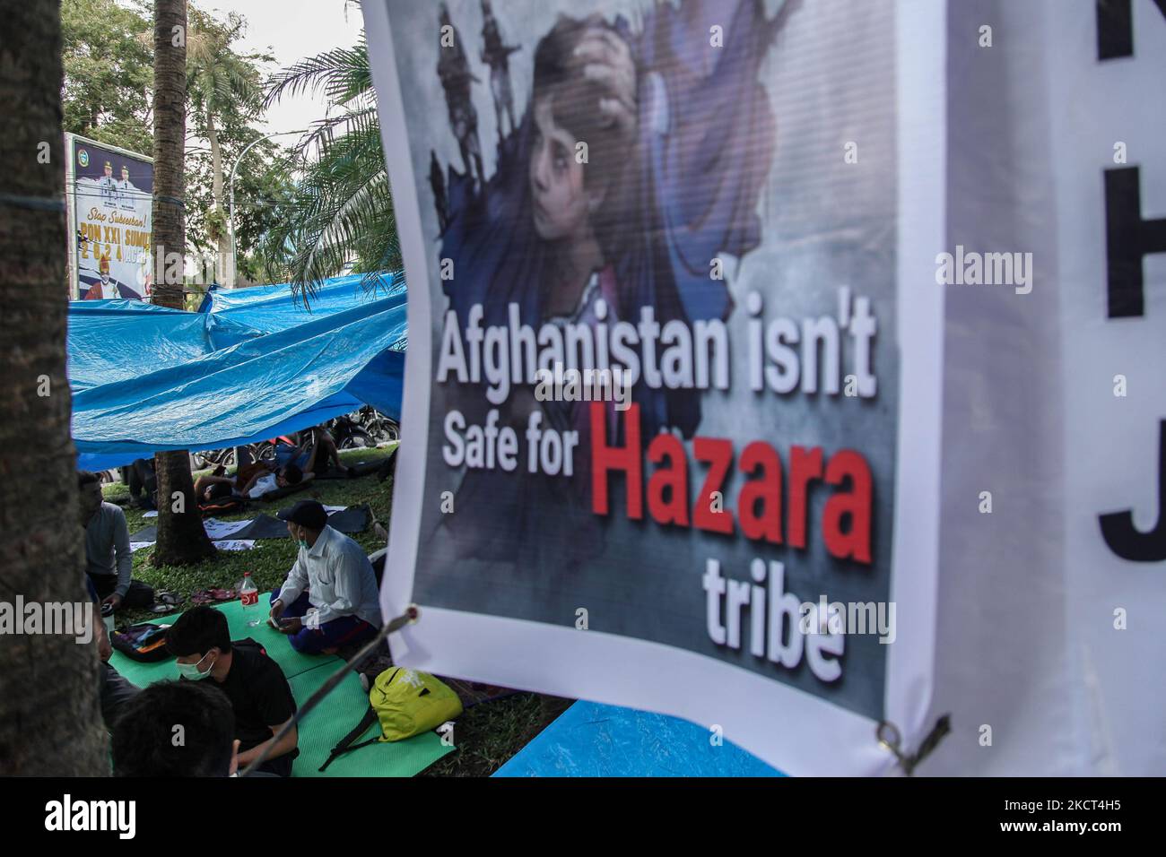 Afghan refugee men living in Indonesia sit in their tent during a ...