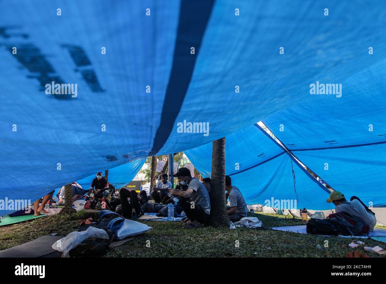 Afghan refugee men living in Indonesia sit in their tent during a ...