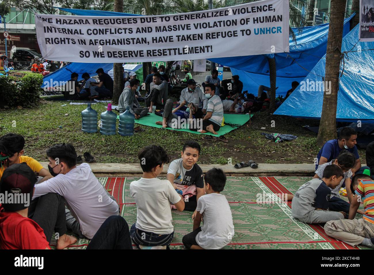 Afghan refugee men living in Indonesia sit in their tent during a ...
