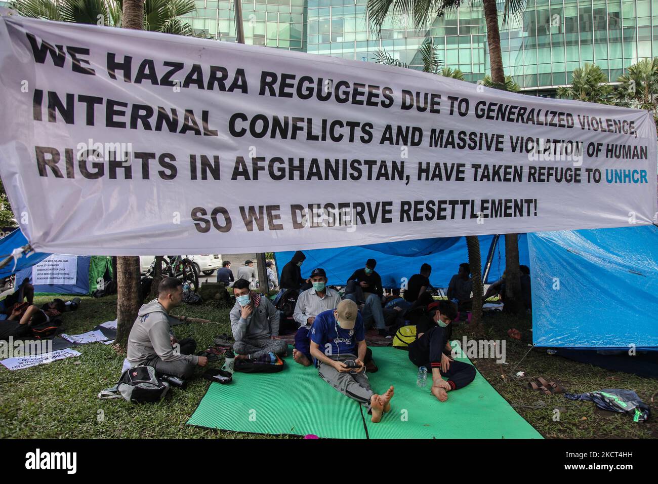 Afghan refugee men living in Indonesia sit in their tent during a ...