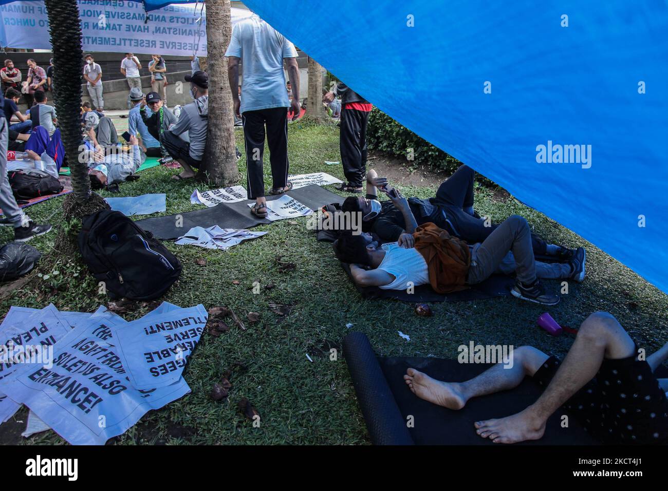 Afghan refugee men living in Indonesia rest in their tent during a ...