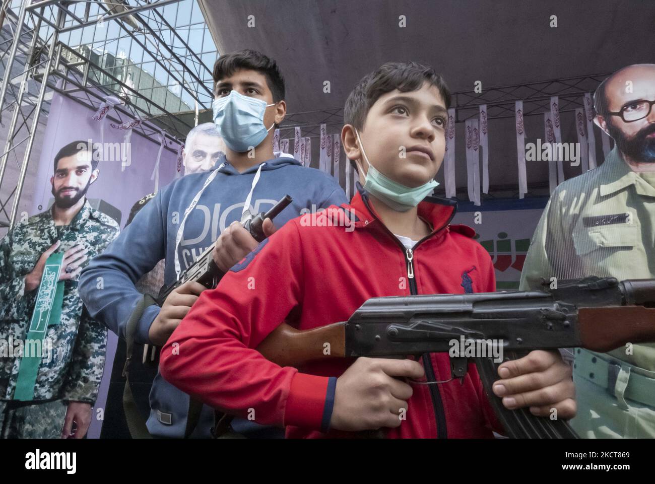 Iranian schoolboys hold AK-47 and a UZI guns as they pose for ...