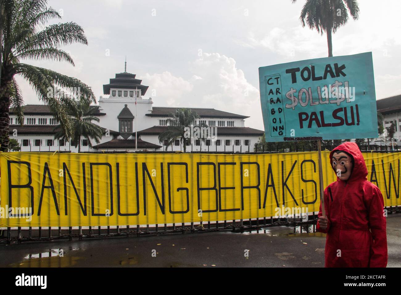 A man dressed as in the movie series "Money Heist" holds a placard ...