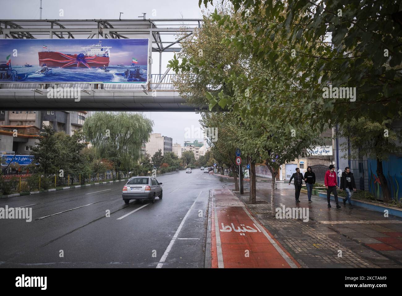 Iranian youths walk along a street-side as an anti-U.S. billboard has ...