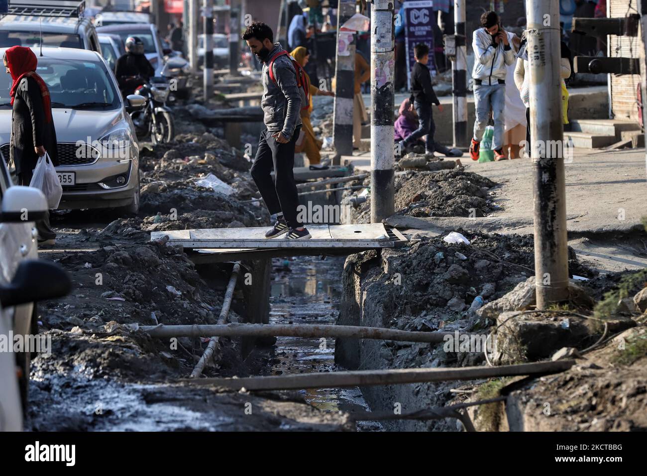 A man crosses an Uncovered sewer drain in Main Market Baramulla, Jammu ...