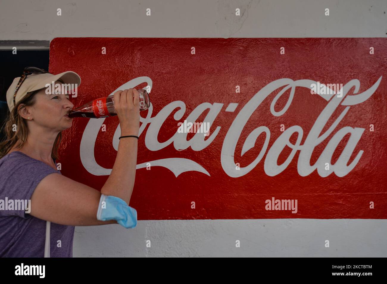 A woman is drinking Coca-Cola near Playacar Beach in Playa del Carmen ...
