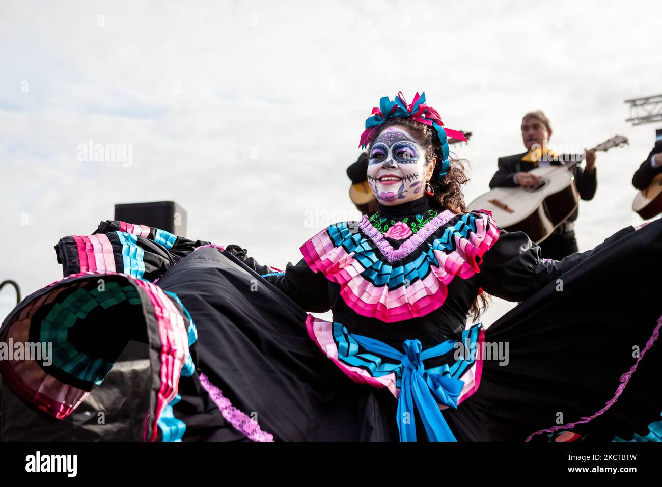 A woman dressed as a Catrina dances to the music of a mariachi band ...