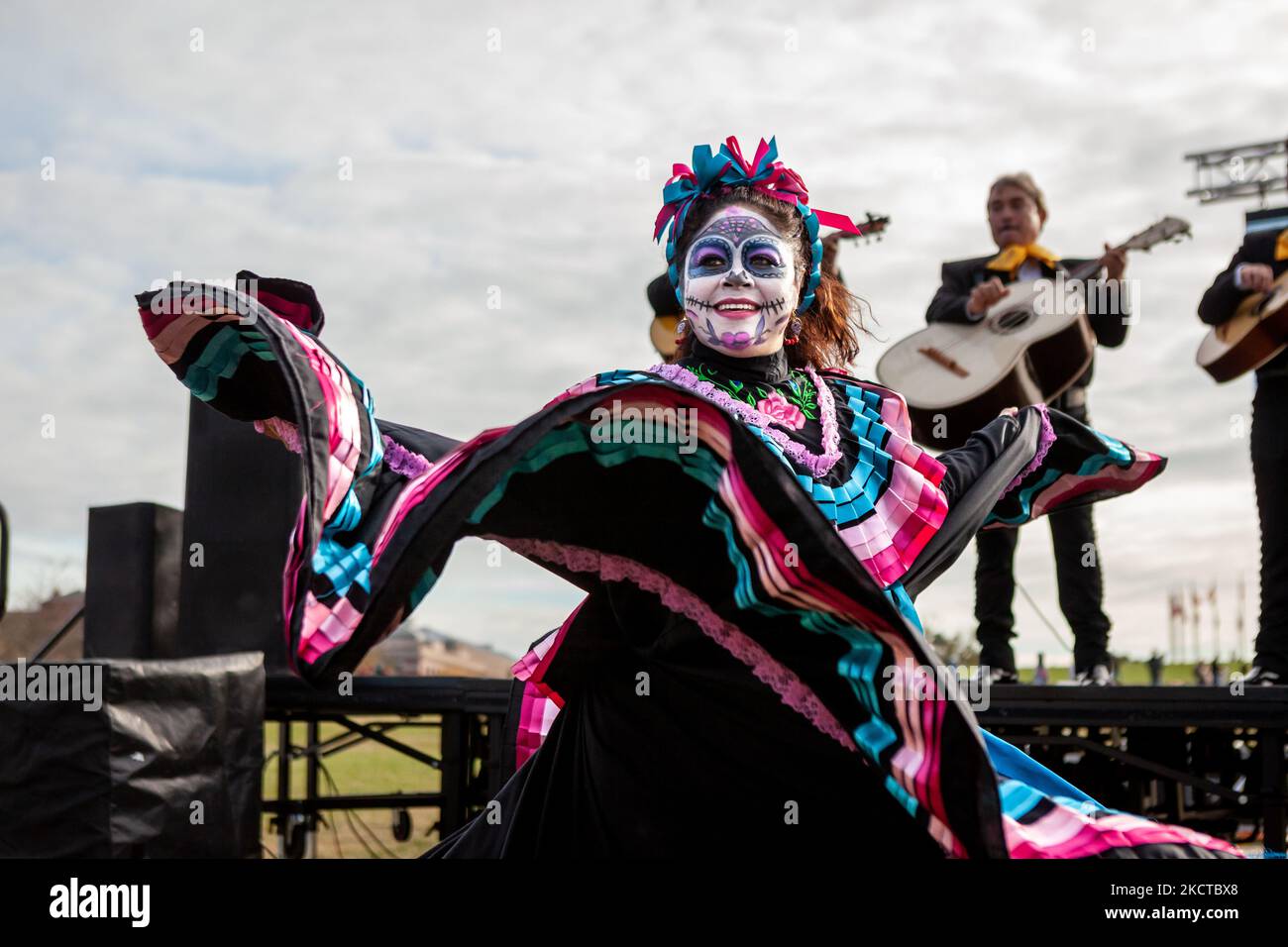A woman dressed as a Catrina dances to the music of a mariachi band ...